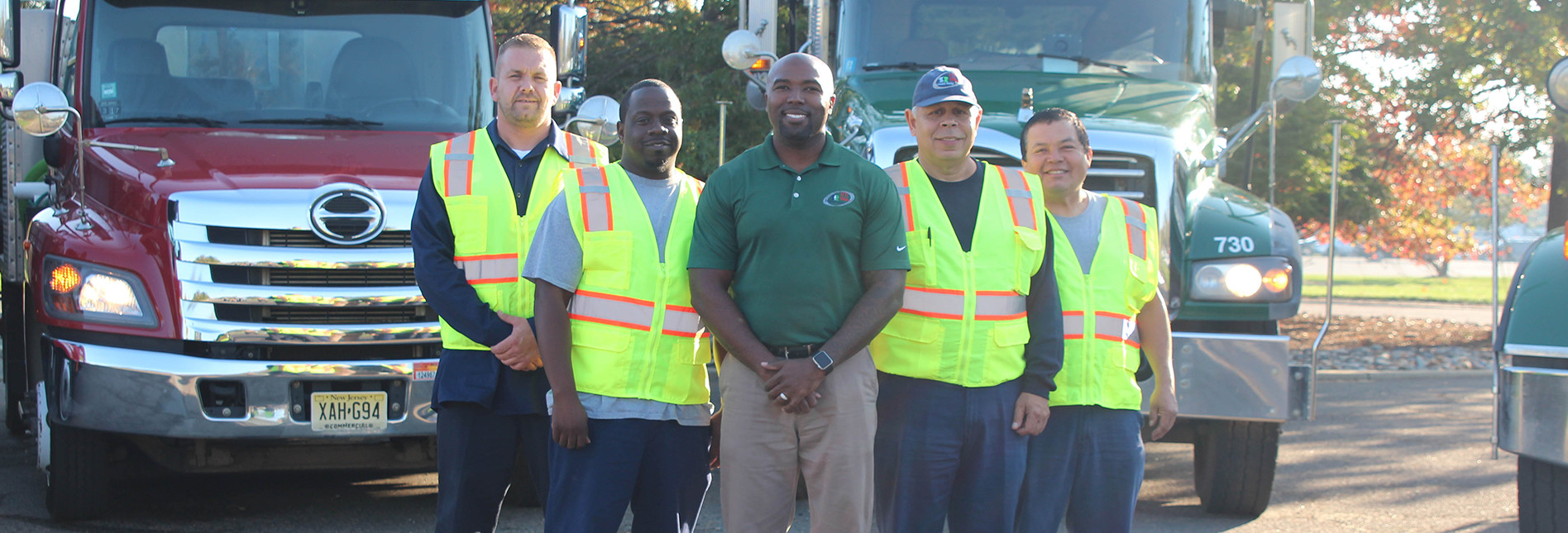 5 employees standing in front of three trucks - Russell Reid